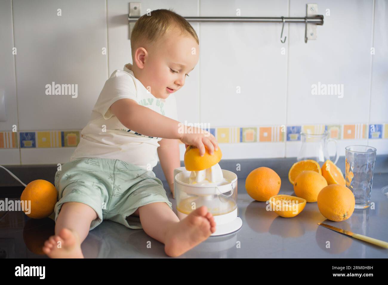 a boy child makes freshly squeezed orange juice on a manual juicer ...