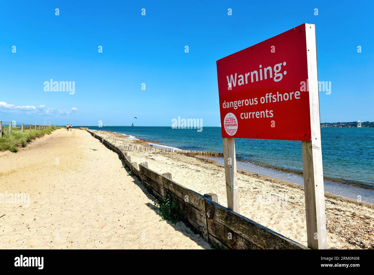 A large red sign on the beach warning the public of 'Dangerous Offshore ...
