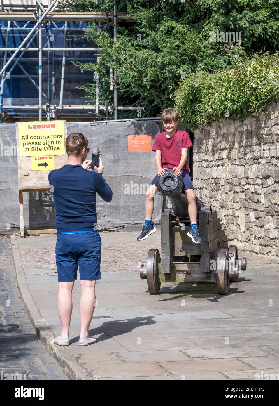 Parent taking photo of son sitting on old canon barrel, Castle Hill ...