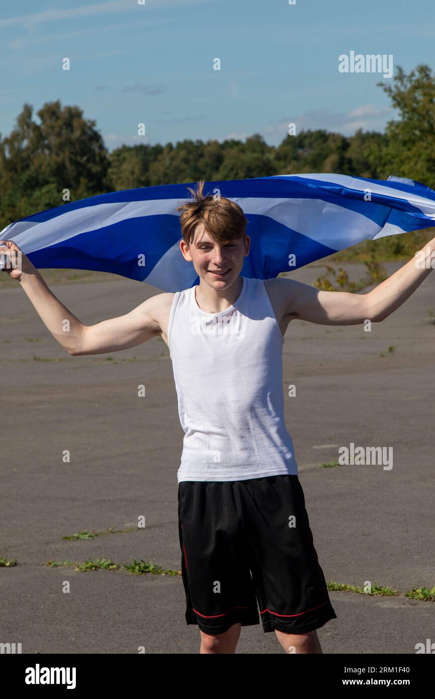 A happy and laughing teenage boy waving the Scottish Flag Stock Photo ...