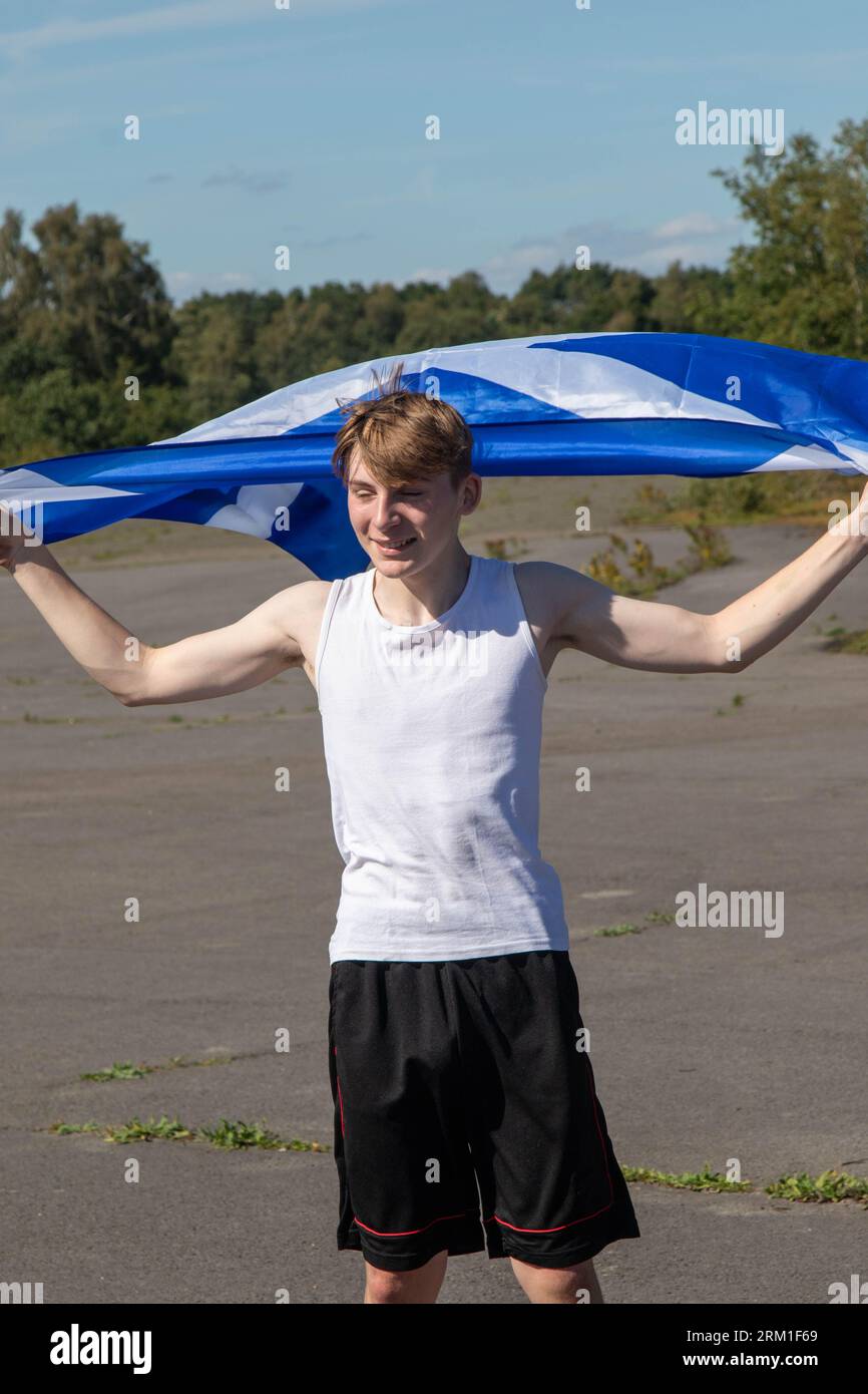 A happy and laughing teenage boy waving the Scottish Flag Stock Photo ...