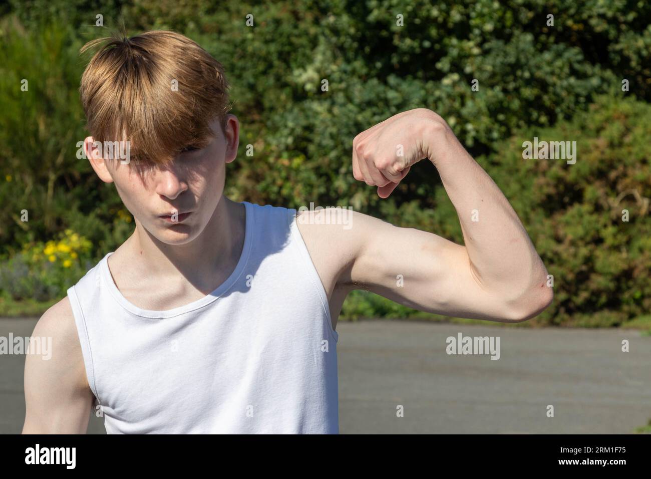 Fit and sporty teenage boy flexing his bicep Stock Photo - Alamy