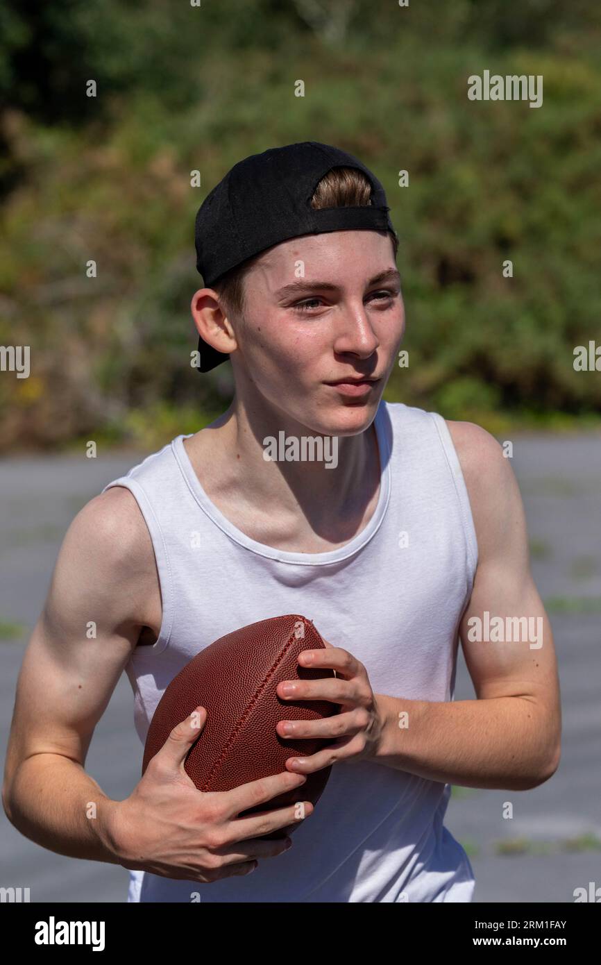 Fit and active teenage boy running outside with an American Football ...