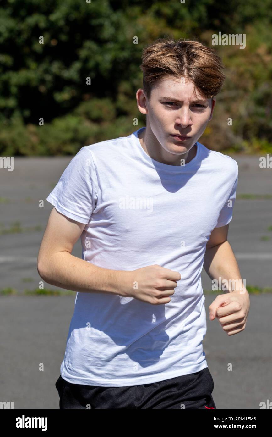 Fit and sporty teenage boy running during a warm summer’s afternoon ...