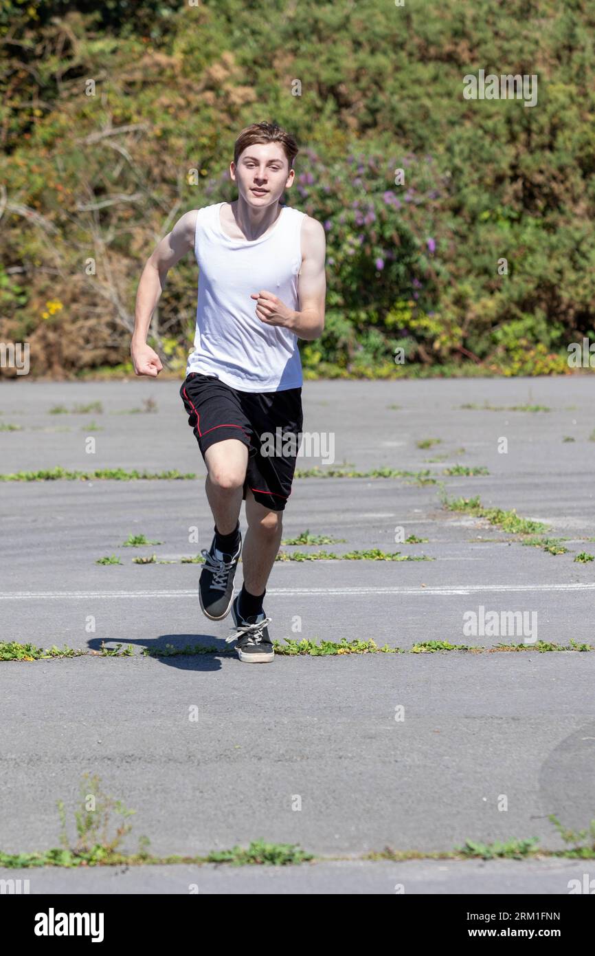 Fit and sporty teenage boy running during a warm summer’s afternoon ...