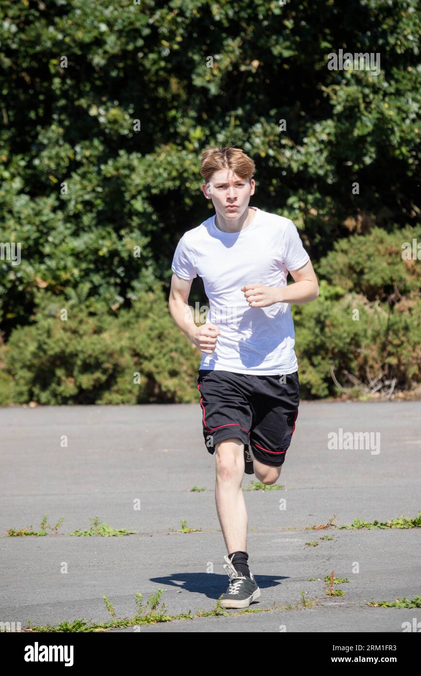 Fit and sporty teenage boy running during a warm summer’s afternoon ...