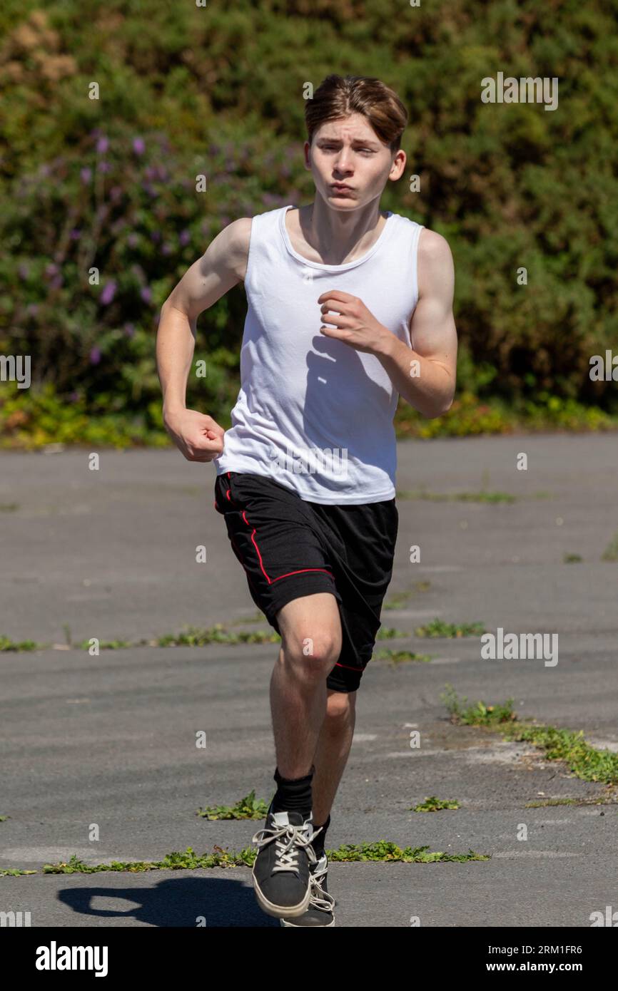Fit and sporty teenage boy running during a warm summer’s afternoon ...