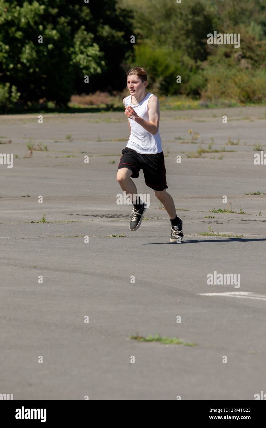 Fit and sporty teenage boy running during a warm summer’s afternoon ...