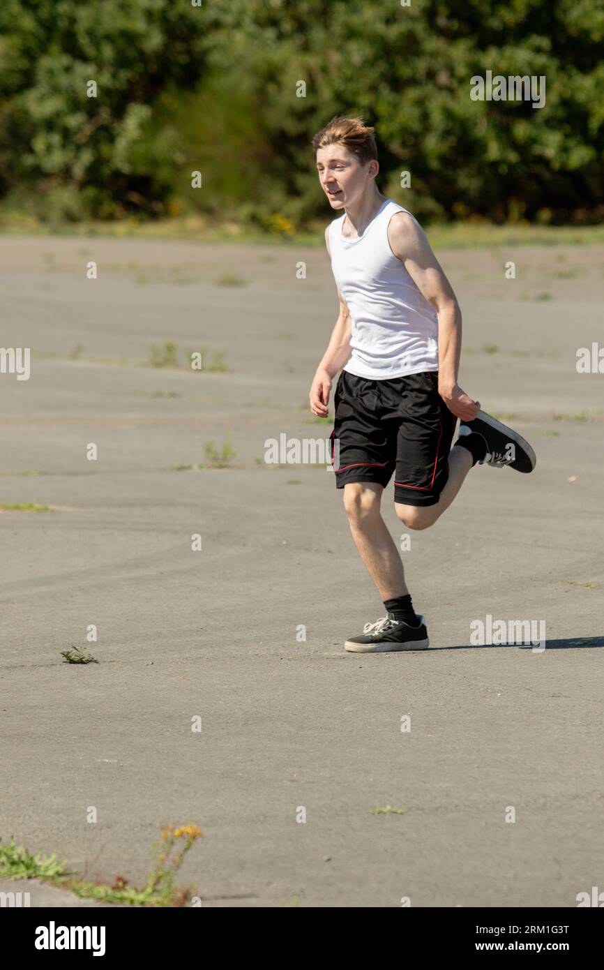 Fit and sporty teenage boy running during a warm summer’s afternoon ...