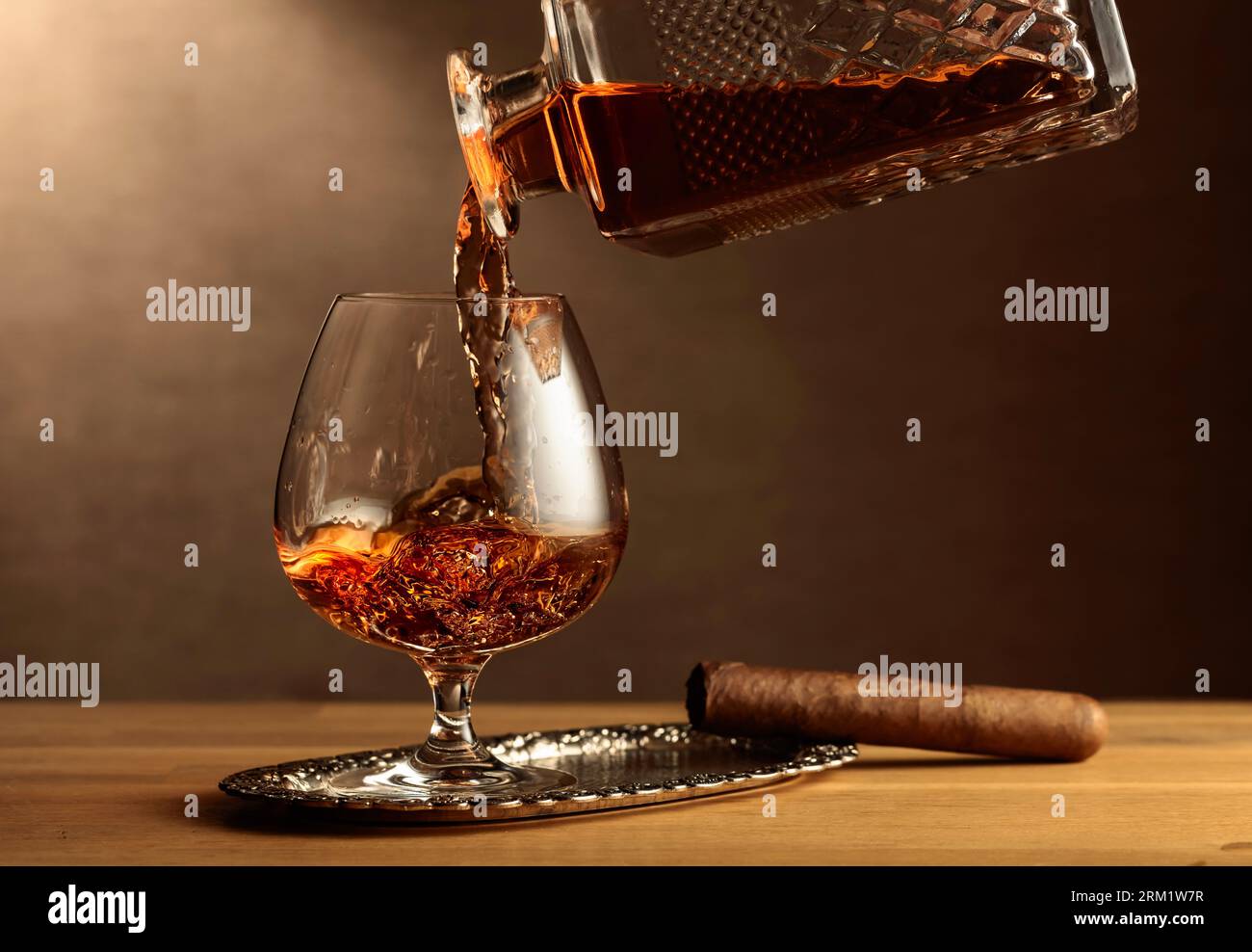 Brandy is poured from a decanter into a snifter glass. Cognac and cigar ...