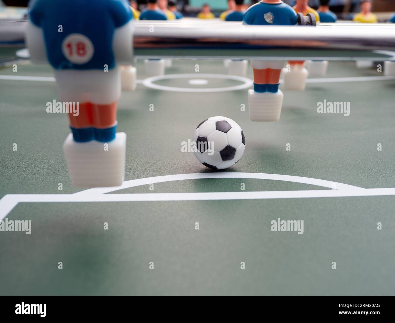 A close-up of some players and a soccer ball on a foosball table. Board ...