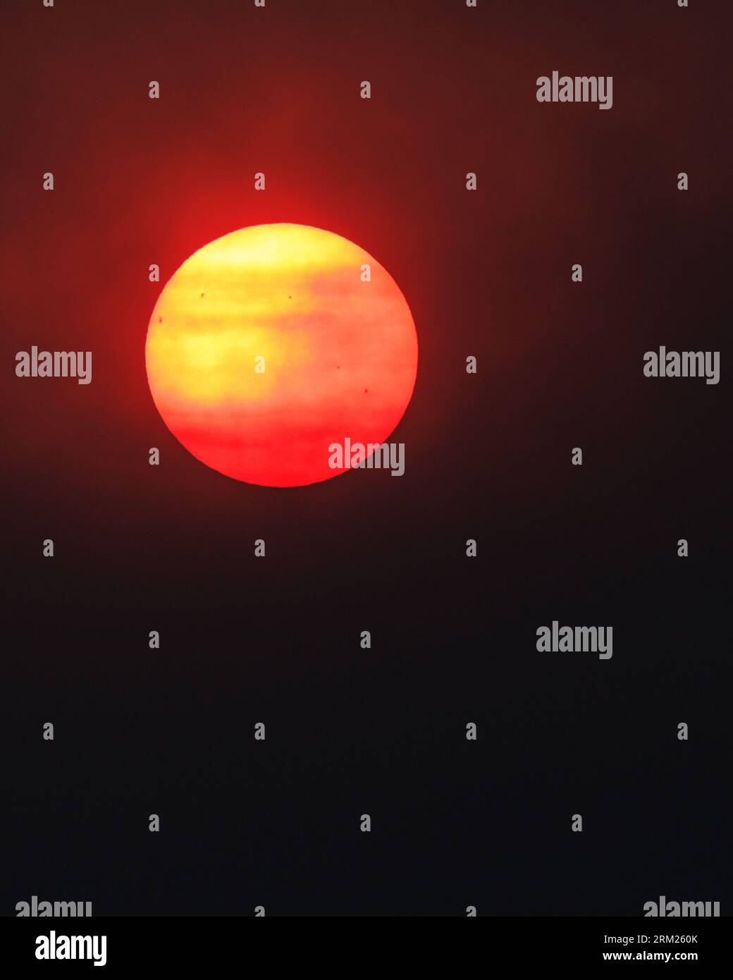 Red round sun covered by smoke from forest wildfire, close up shot ...