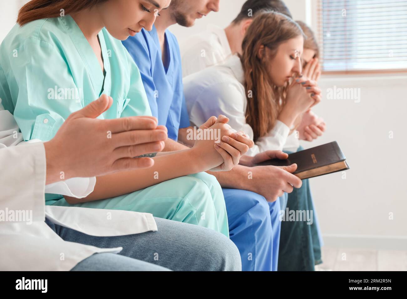 Group of doctors praying with Holy Bible in clinic, closeup Stock Photo ...