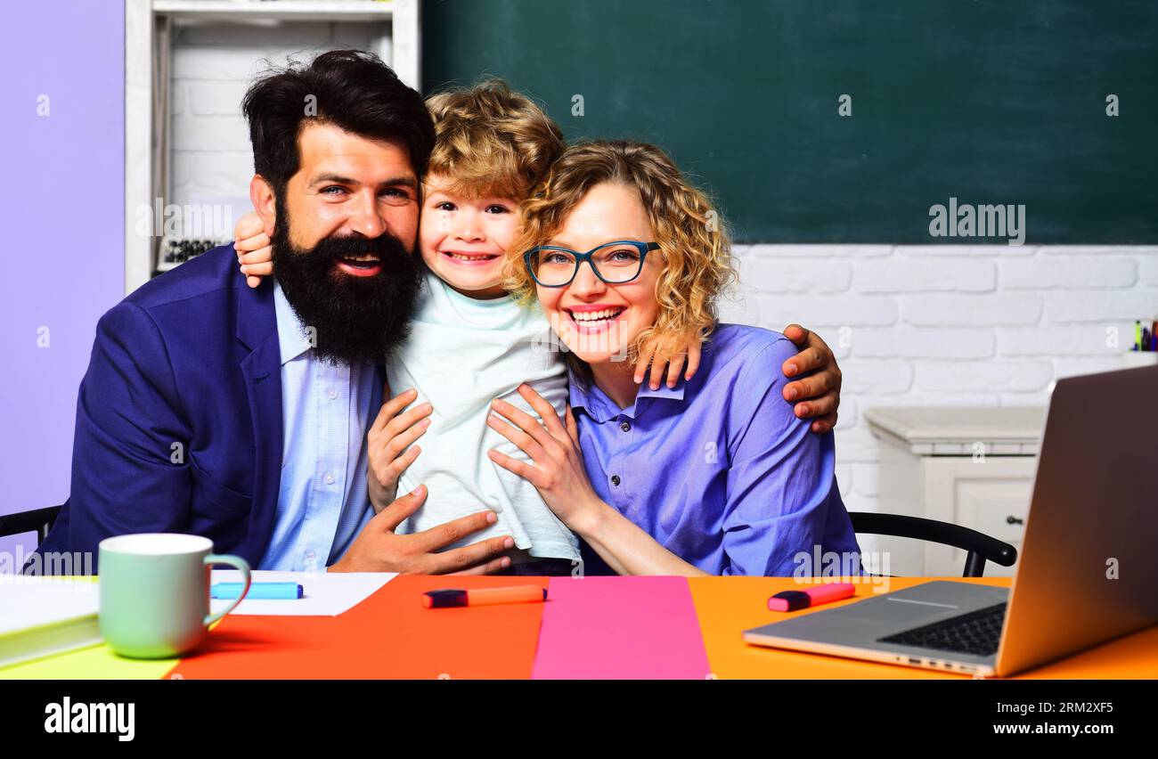 Elementary student. Happy male and female teachers hugging with little ...