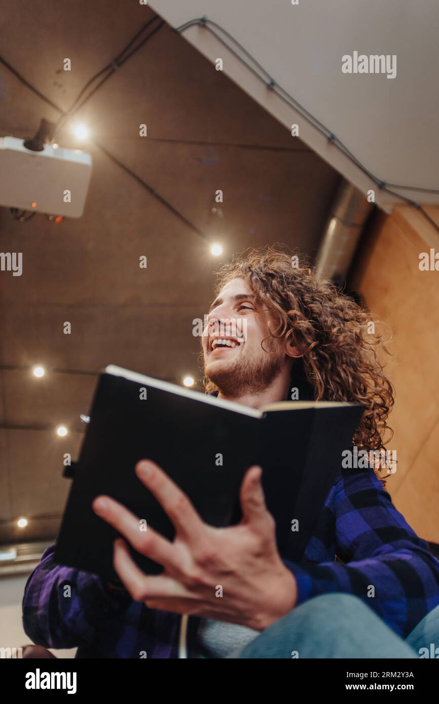 Low angle shot of male person with long hair writing notes down in a ...