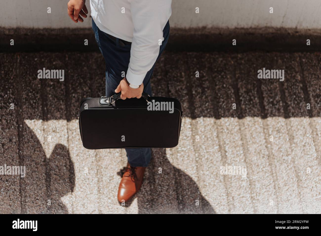 Formal professional businessman outside in the sun holding a briefcase ...