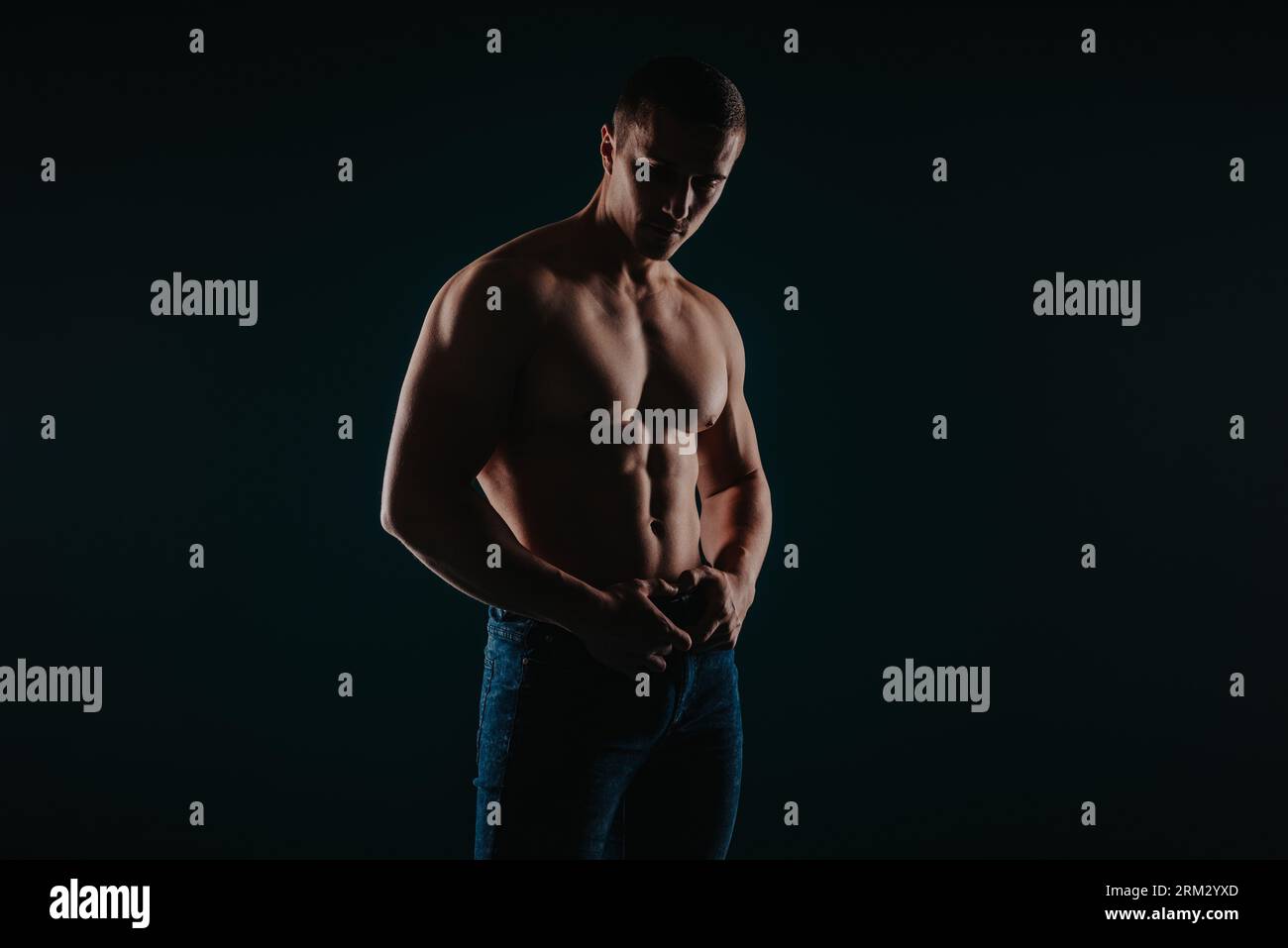 Well-built and attractive man standing in a dark room and posing Stock ...