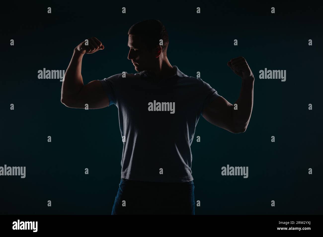 Appealing and well-built man standing in a dark room and flexing his ...