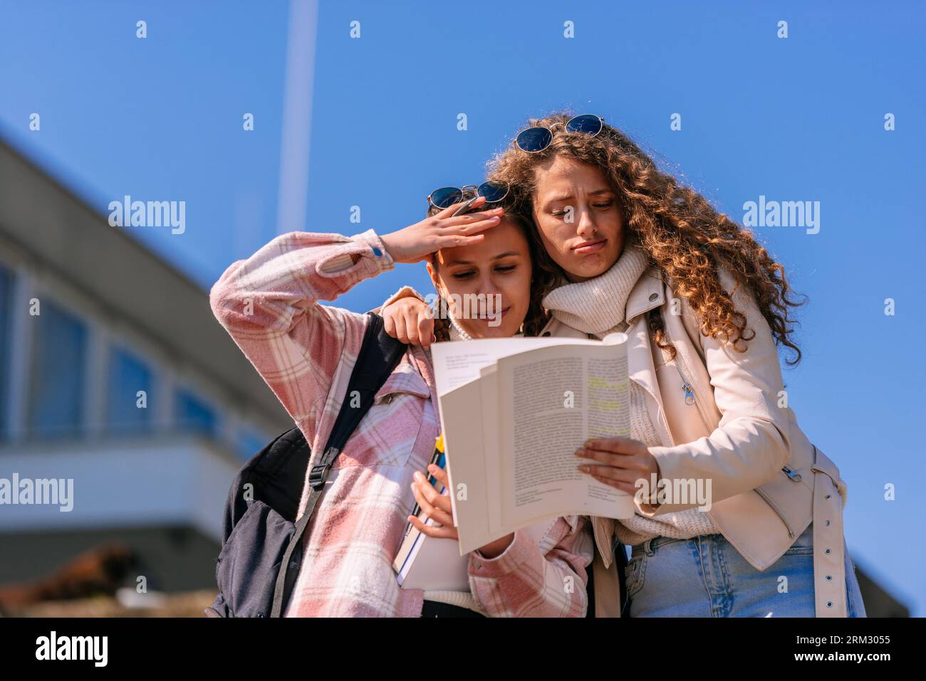 Two high school girls are reading a book together Stock Photo - Alamy