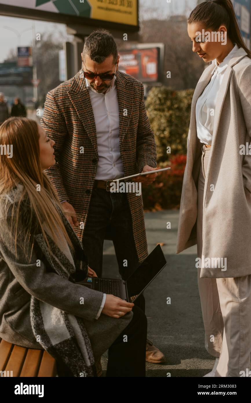 Three business people talking while two of them standing and the other ...