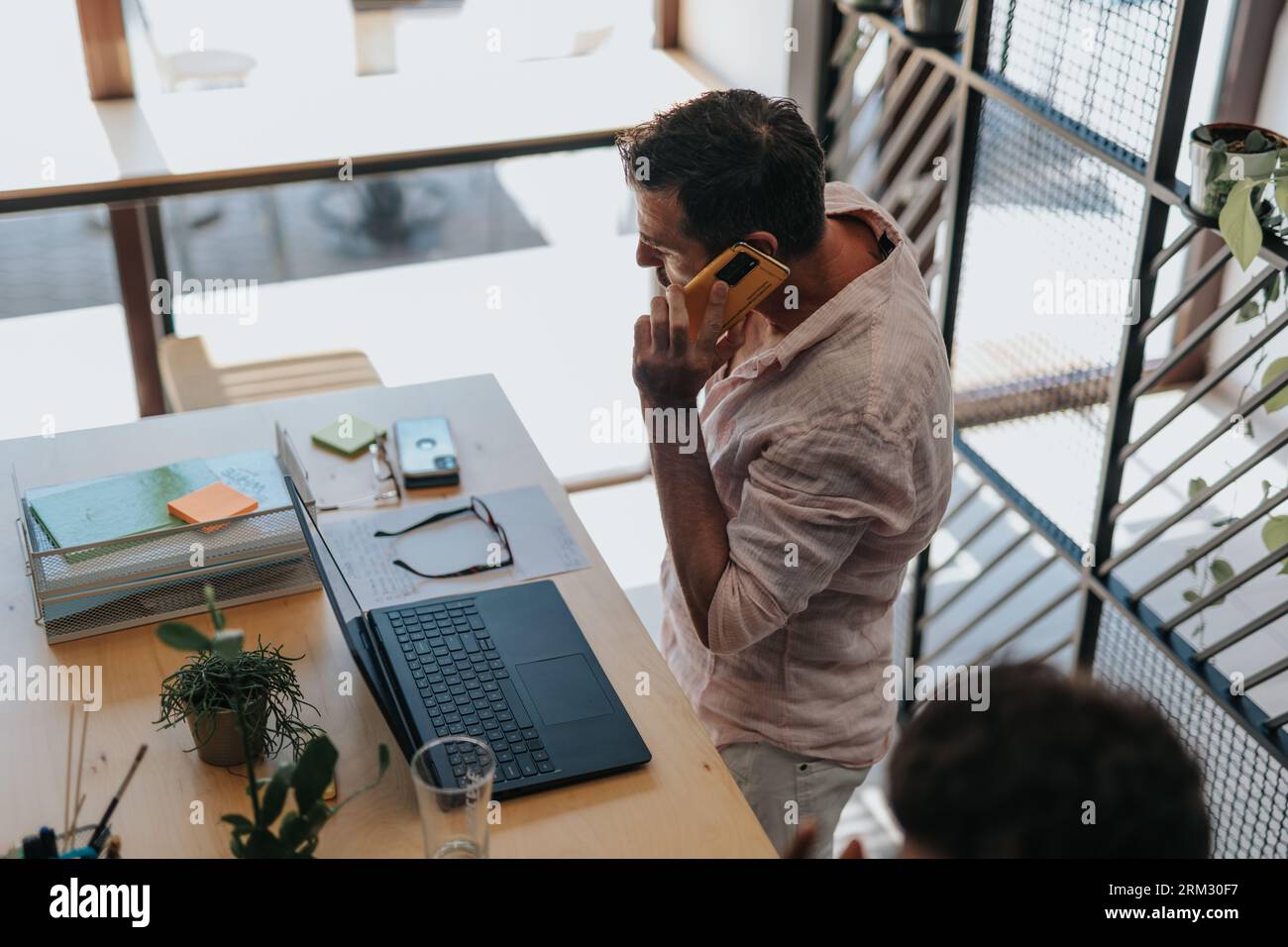 Businessman having phone call while working alone at modern workshop on ...