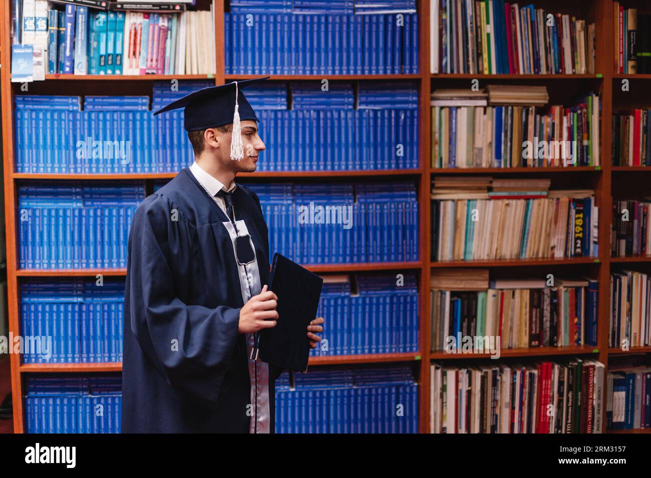 Young male graduate posing in the library for their photo shoot for the ...