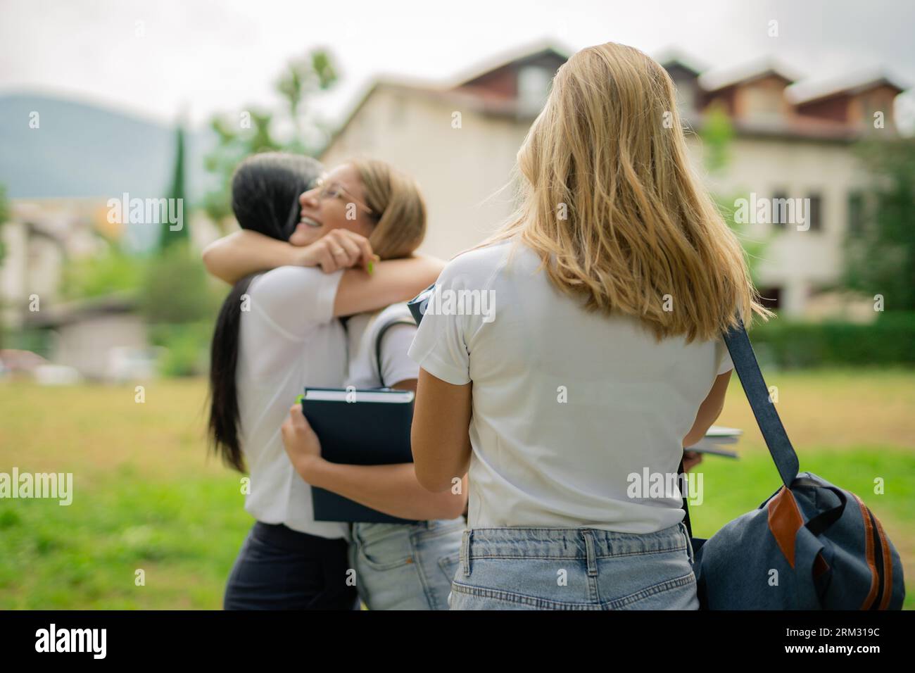 Group of teenage high school students standing outside, hugging ...