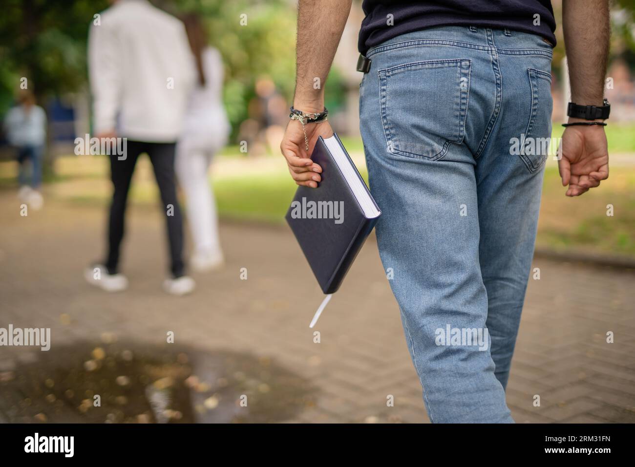 Low-angle of a man walking with a notebook in his hand, faculty student ...
