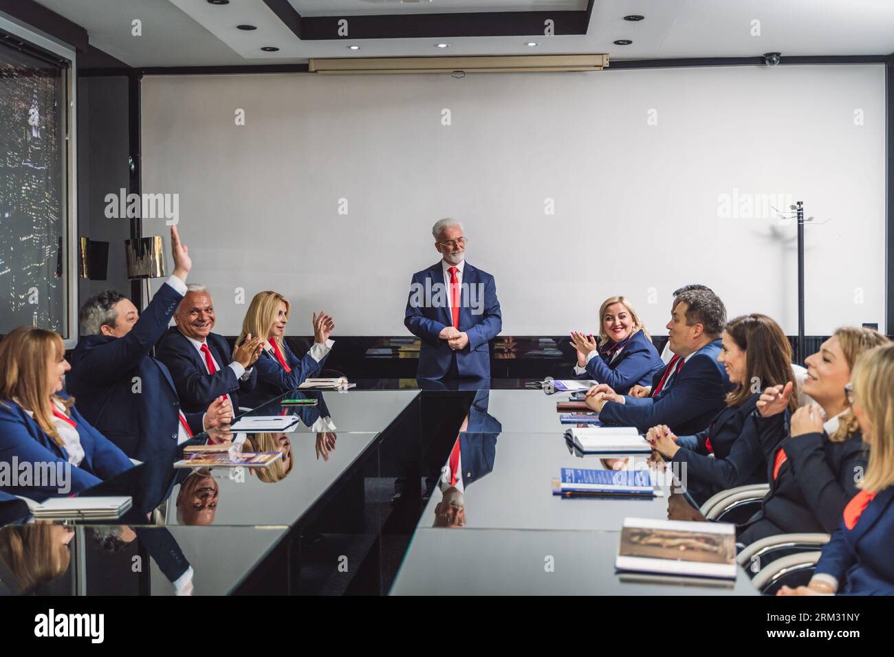 Elderly, successful CEO receiving applause by a group of senior ...