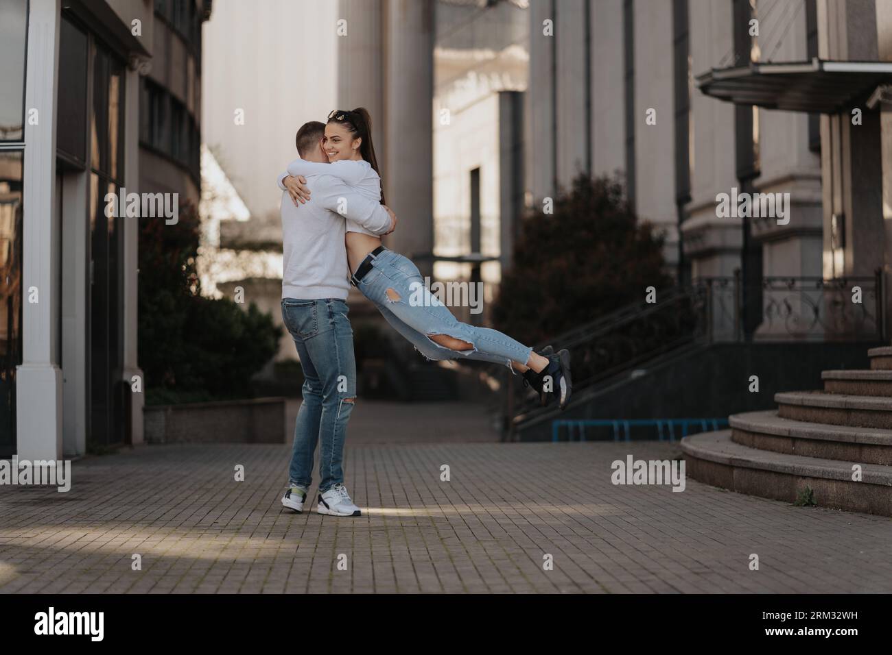 Handsome and strong man lifting and hugging his girlfriend while ...