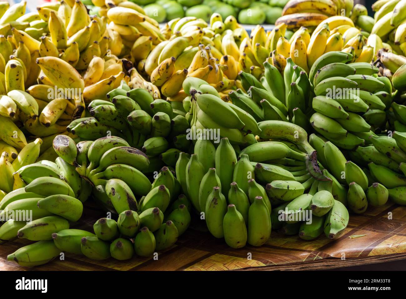 Green and yellow bananas. Local fruits lay on a counter of a ...