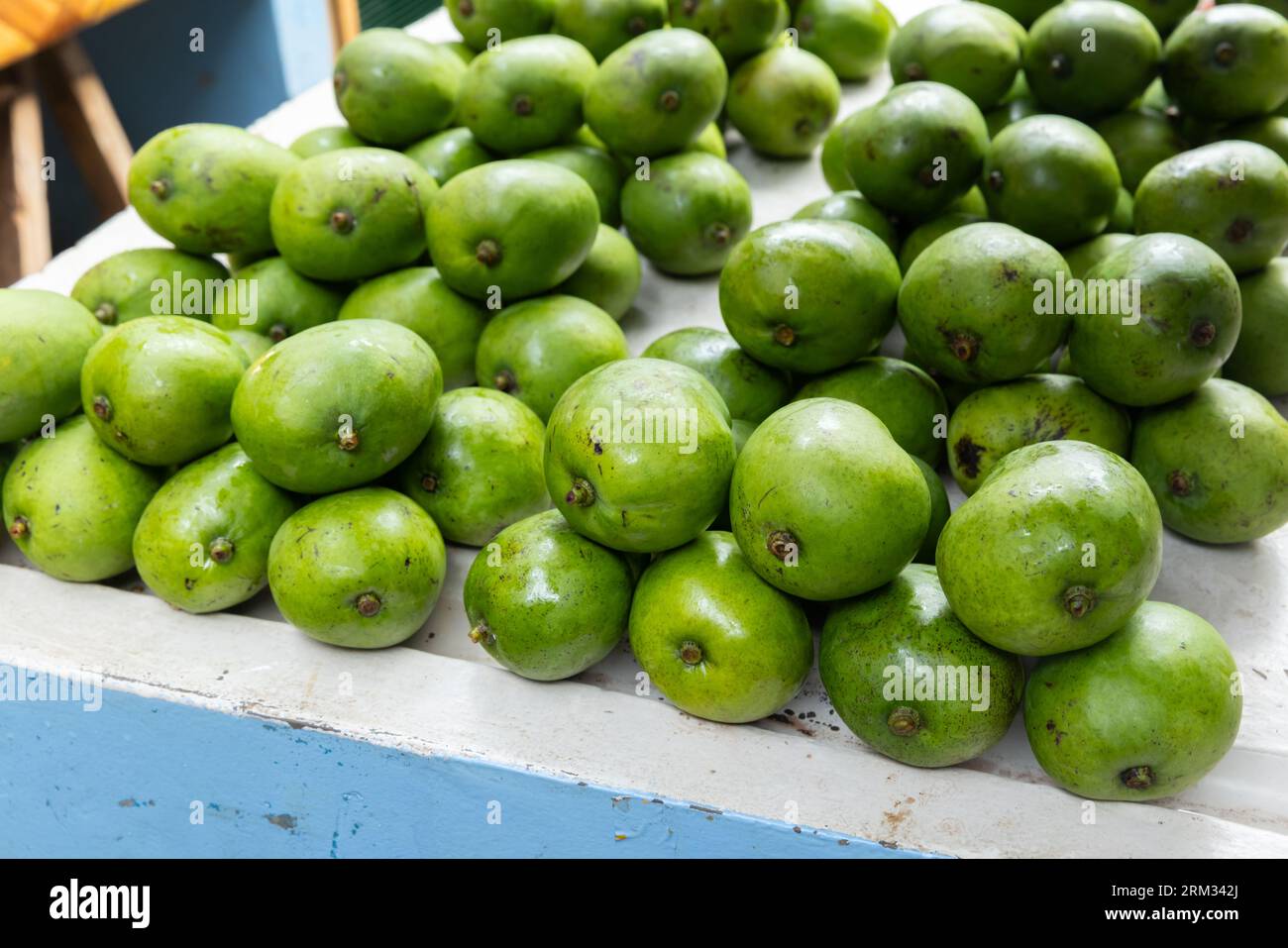 Green mango. Local fruits lay on a counter of a marketplace. Seychelles ...