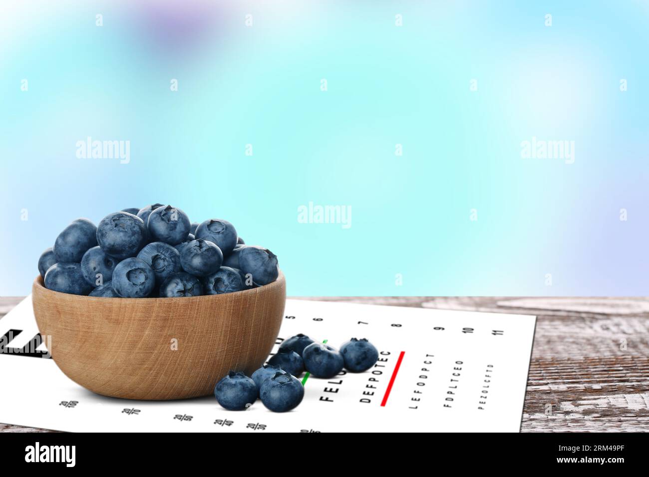 Improving eyesight. Vision test chart and blueberries on wooden table ... Improving eyesight. Vision test chart and blueberries on wooden table ...