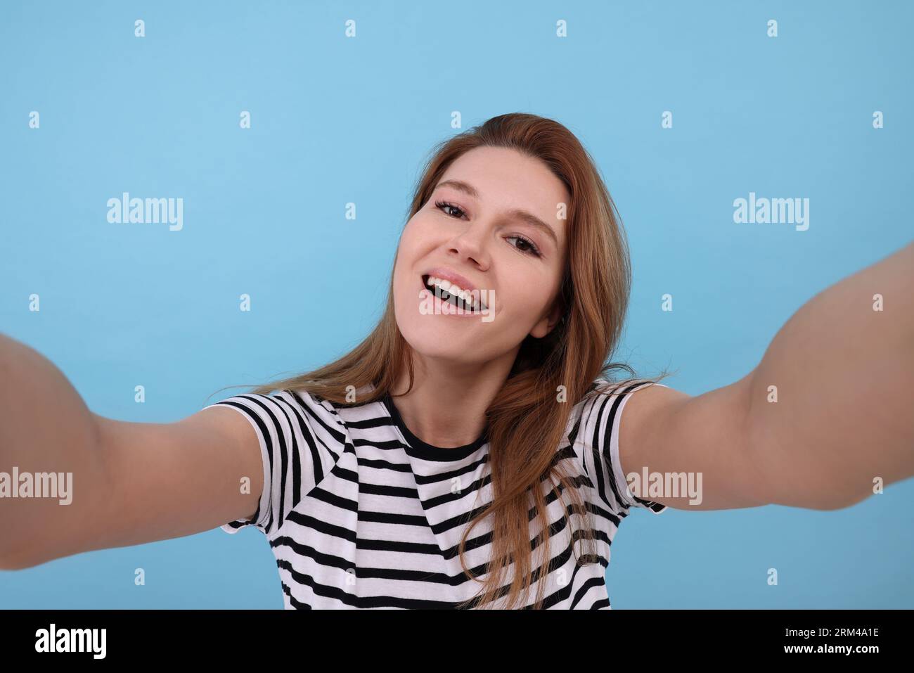 Beautiful woman taking selfie on light blue background Stock Photo - Alamy