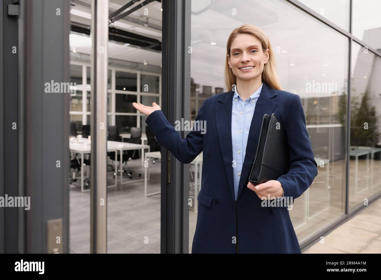 Female real estate agent with leather portfolio inviting inside Stock ...