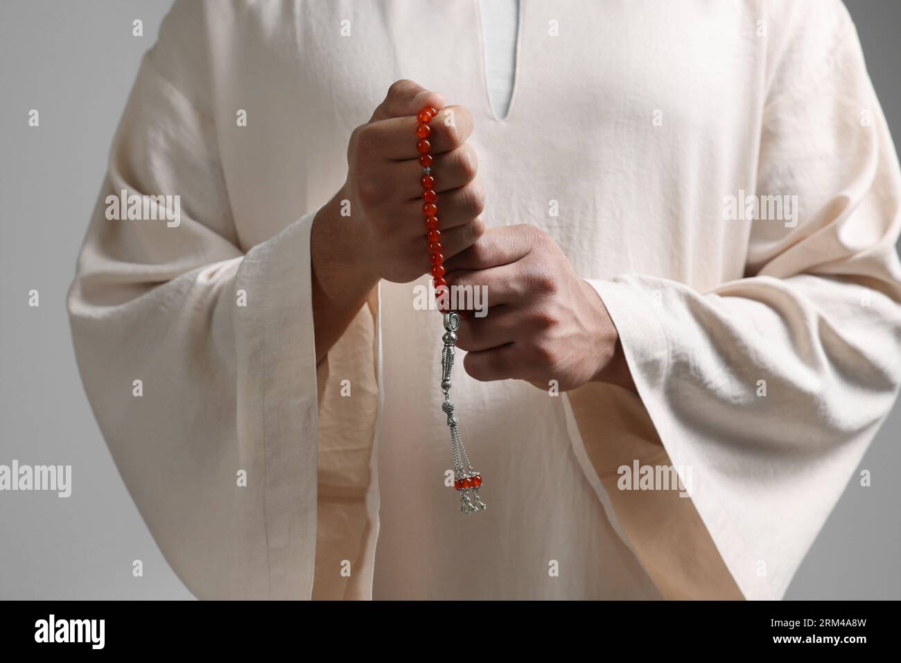 Muslim man with misbaha on light grey background, closeup Stock Photo ...