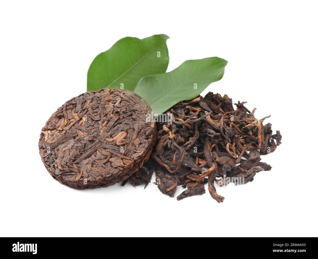 Disc shaped traditional Chinese pu-erh tea and fresh leaves isolated on ...