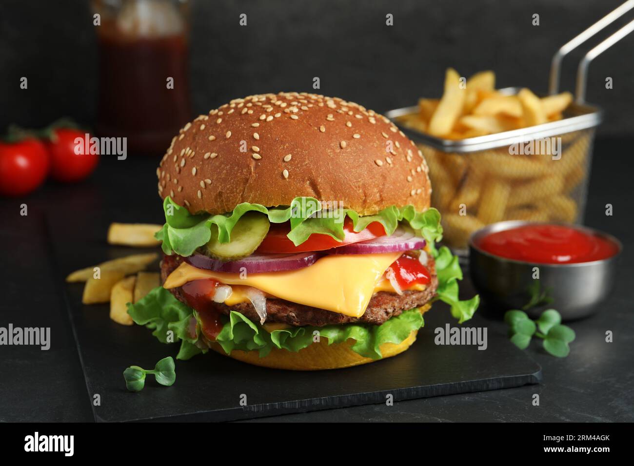Delicious burger with beef patty, french fries and tomato sauce on dark ...