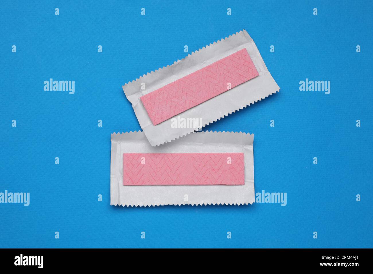 Unwrapped sticks of chewing gum on light blue background, flat lay ...