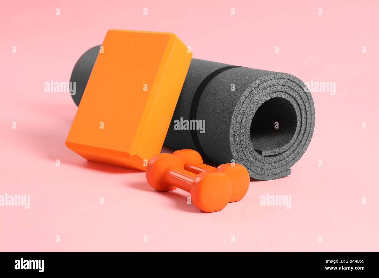 Grey exercise mat, yoga block and dumbbells on pink background Stock ...