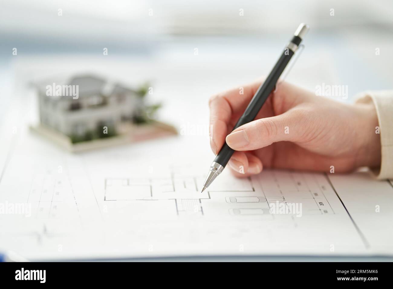 Asian architect writing on building drawings Stock Photo - Alamy
