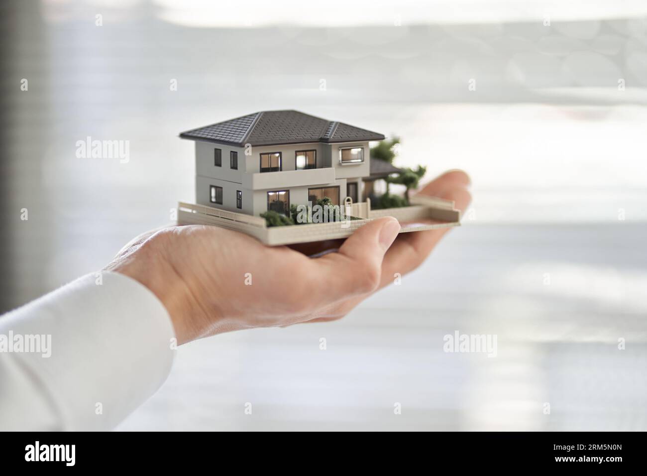 Hands of an Asian man holding an architectural model of a single house ...