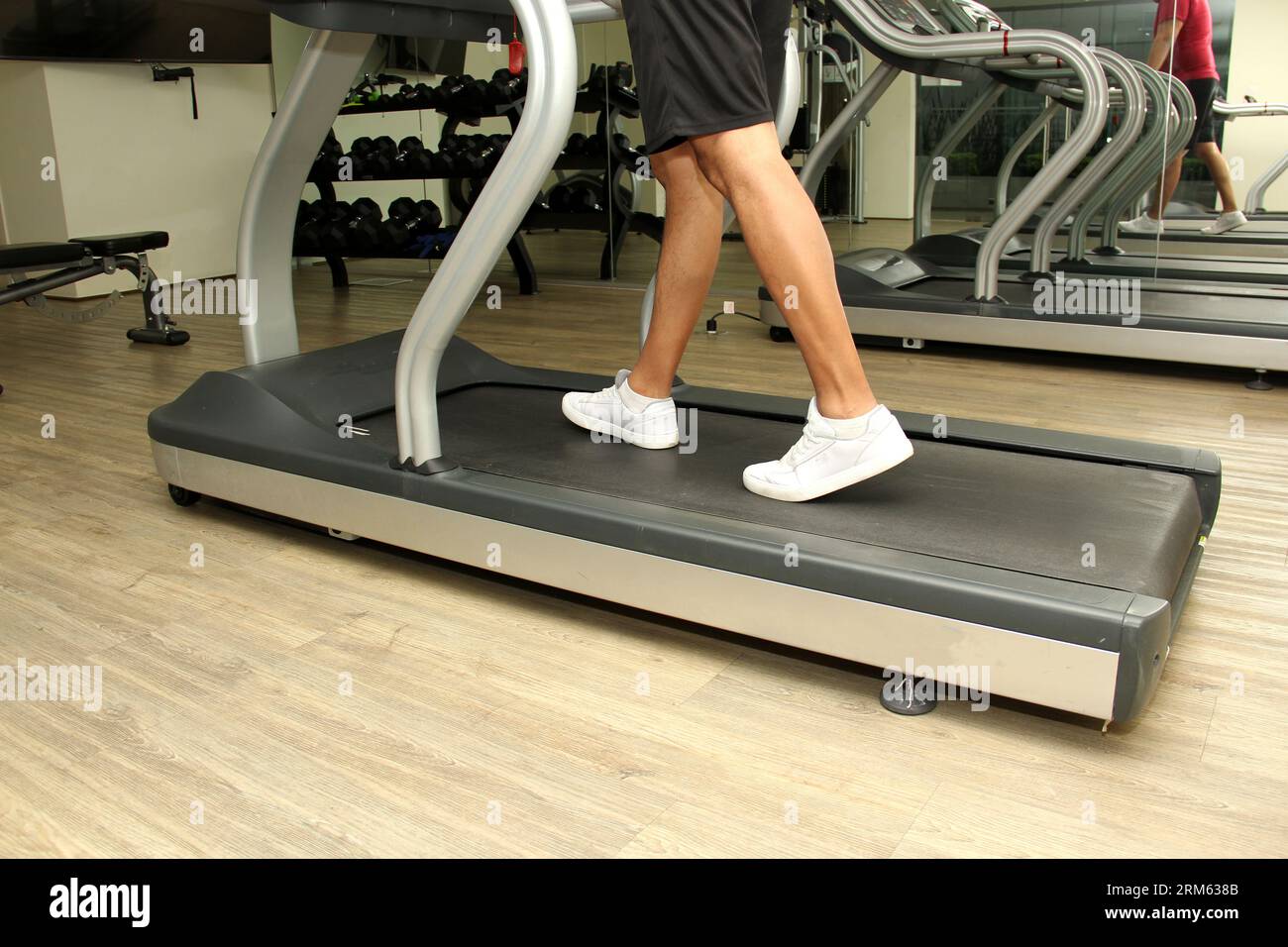 Dark-haired Latino adult man exercises on a treadmill in a gym to lose ...