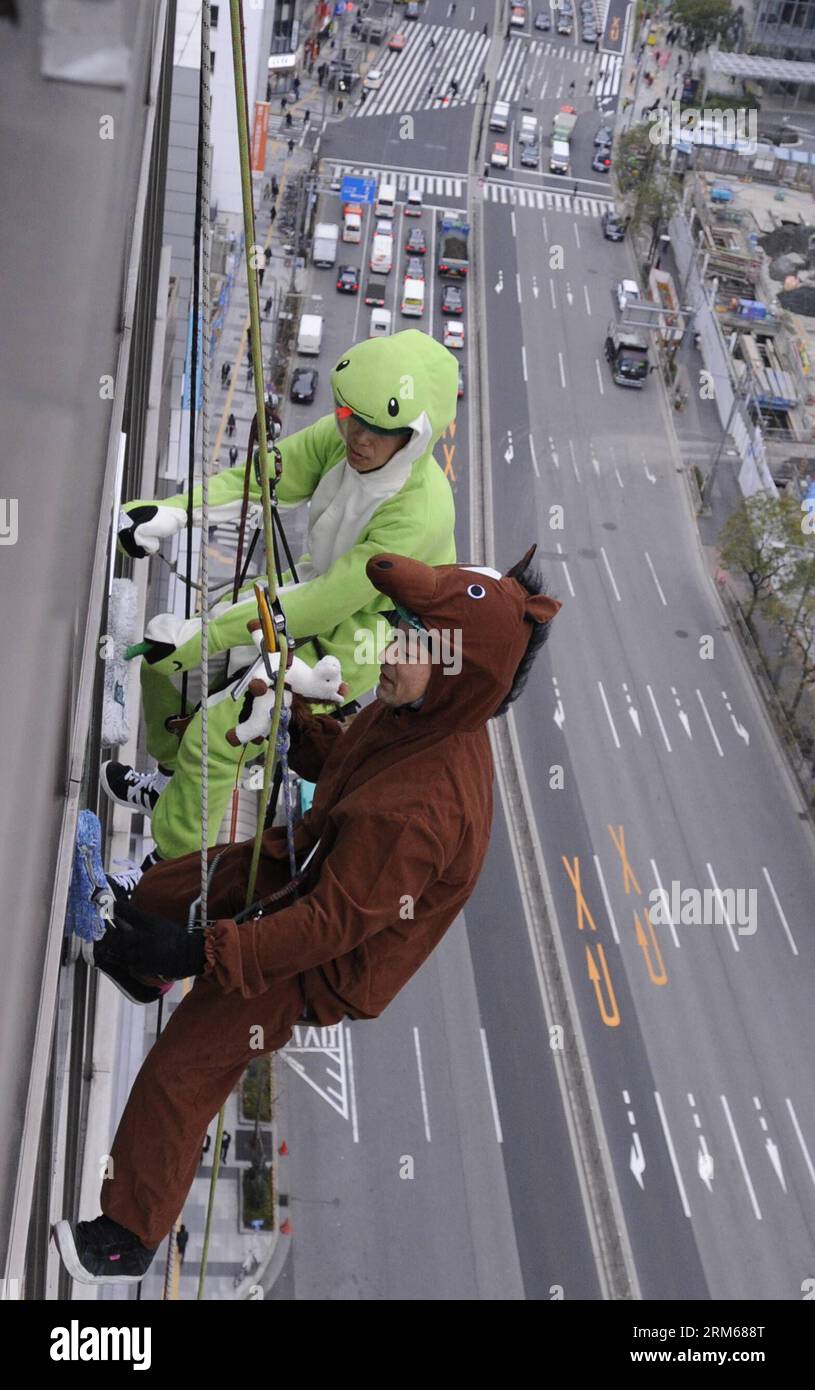 (131218) -- TOKYO, Dec. 18, 2013 (Xinhua) -- Window cleaners clad in ...