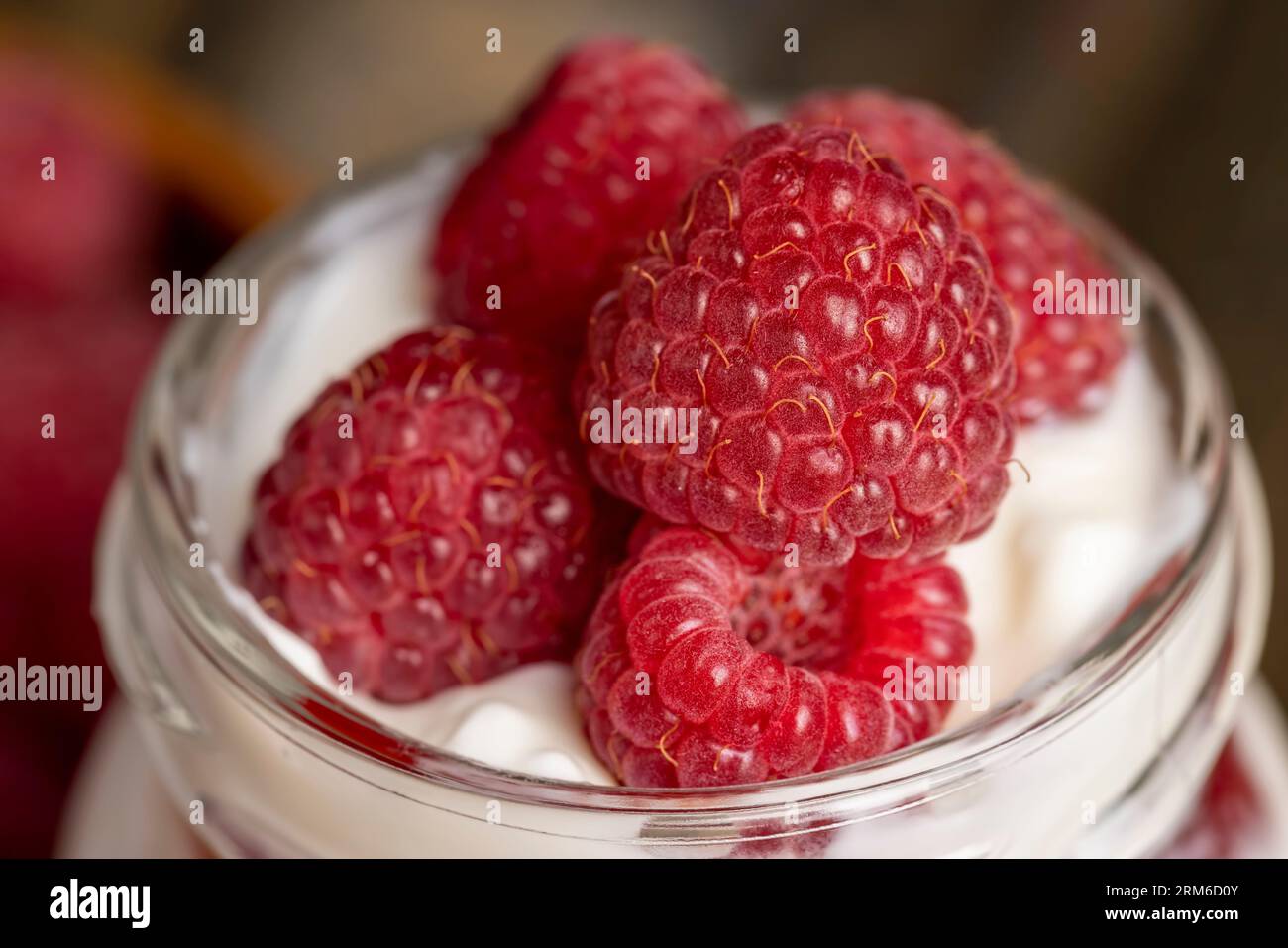 Fresh milk yogurt with whole fresh raspberries, a glass jar with ...