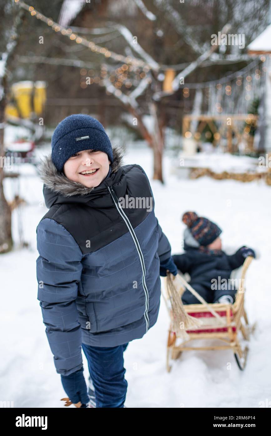 Boy pulling his friend on a sledge Stock Photo - Alamy