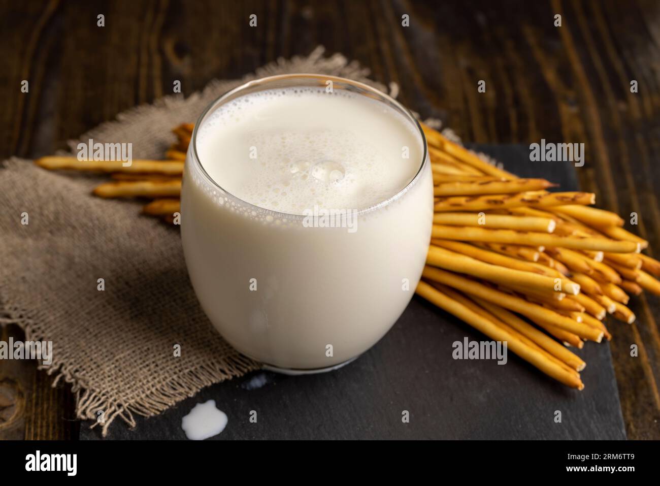Thin and long bread sticks made of wheat flour and a glass of milk ...
