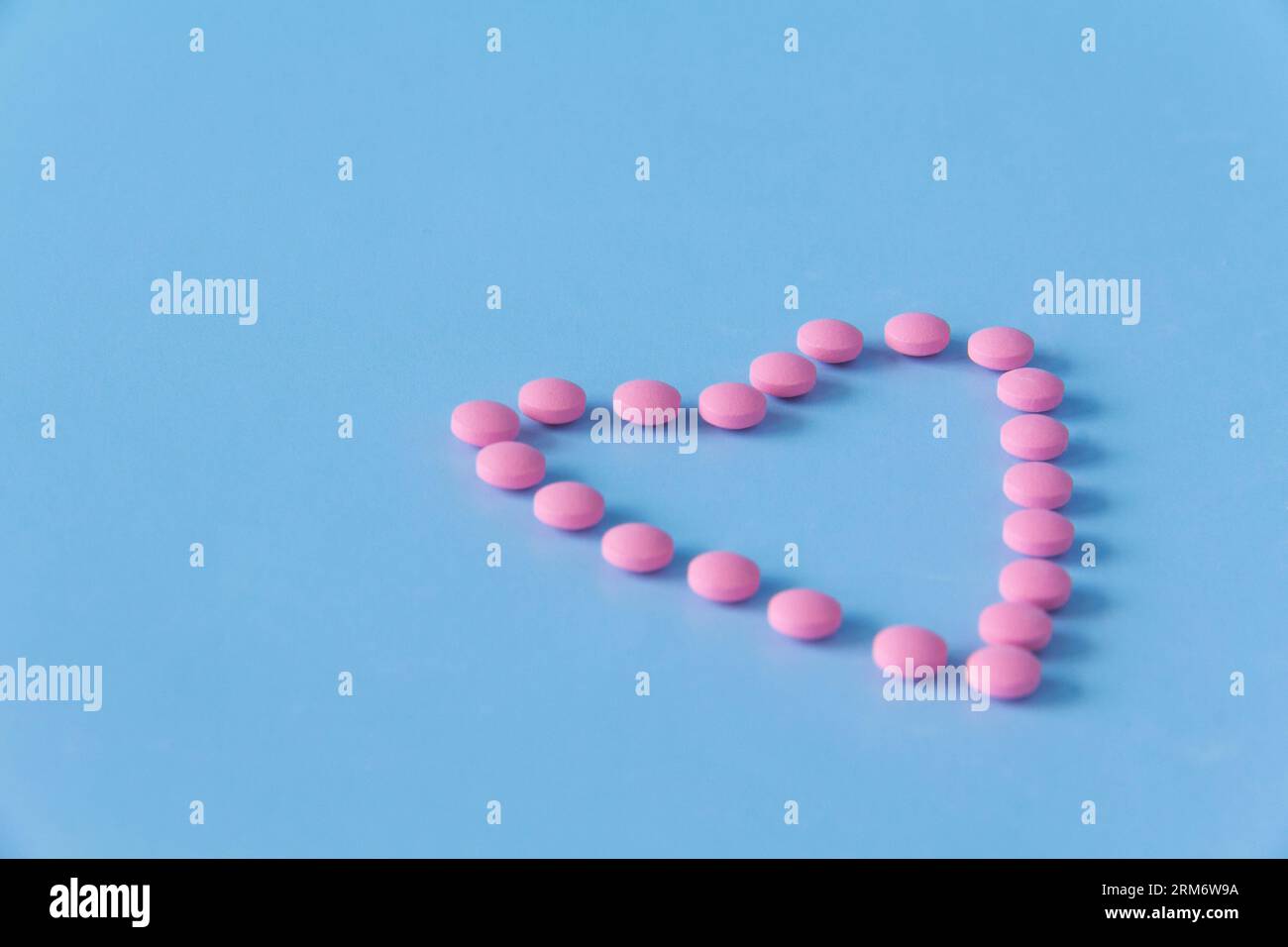Heart made of pink medicines on a blue background. The concept of a ...