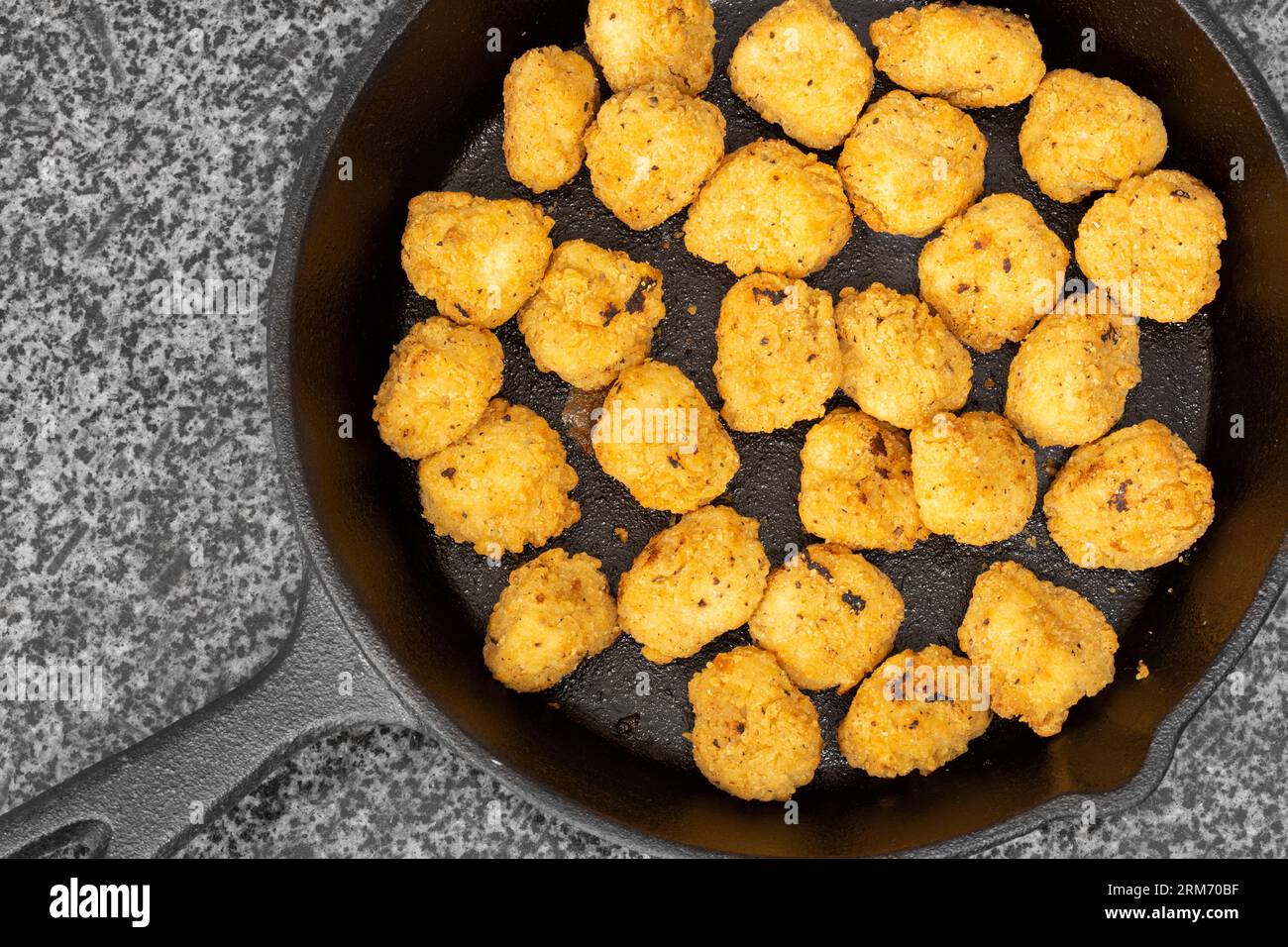 Spicy coated southern fried chicken bites in a cast iron frying pan. On ...