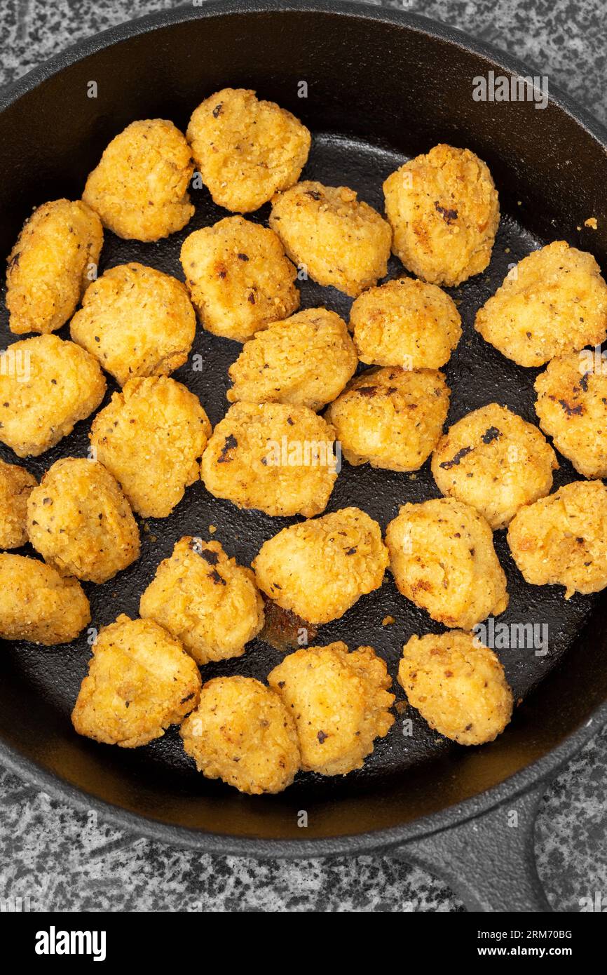 Spicy coated southern fried chicken bites in a cast iron frying pan. On ...